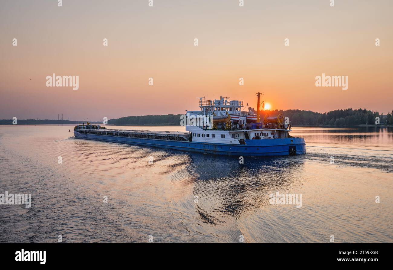A barge floats on the Volga River against the background of Sunset ...