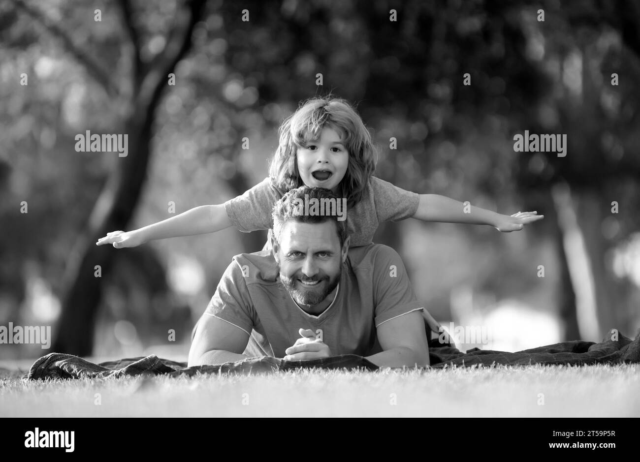 Father piggyback his little son outside, lying on grass. Fathers Day ...