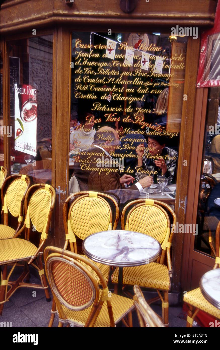 People dining in typical cafe with menu written on the window in Paris ...