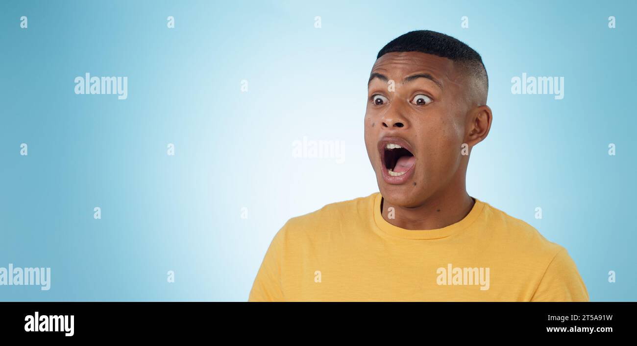 Wow, surprise and shocked man in studio with news, information or ...