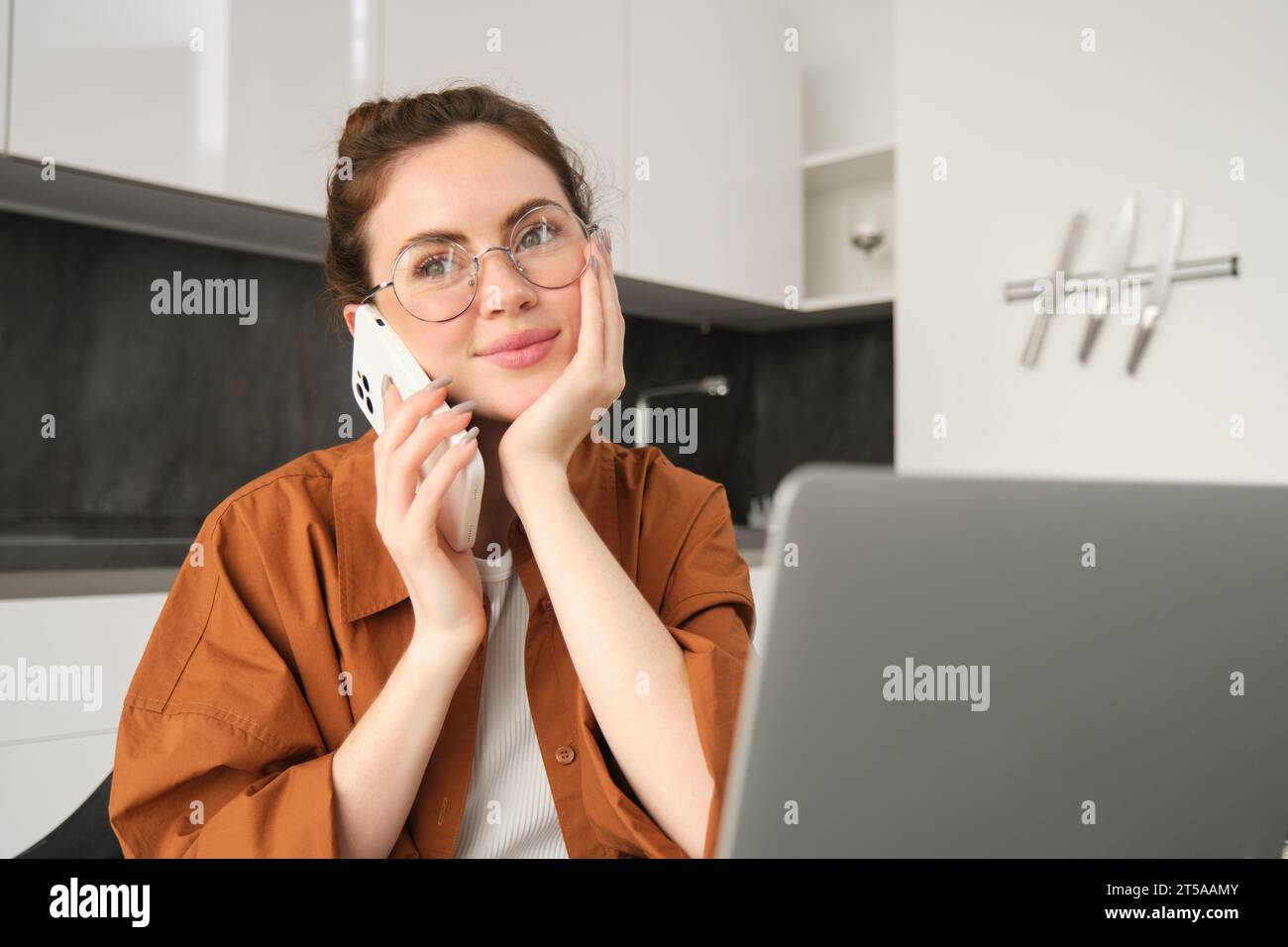 Portrait of beautiful smiling woman working from home, talking on ...