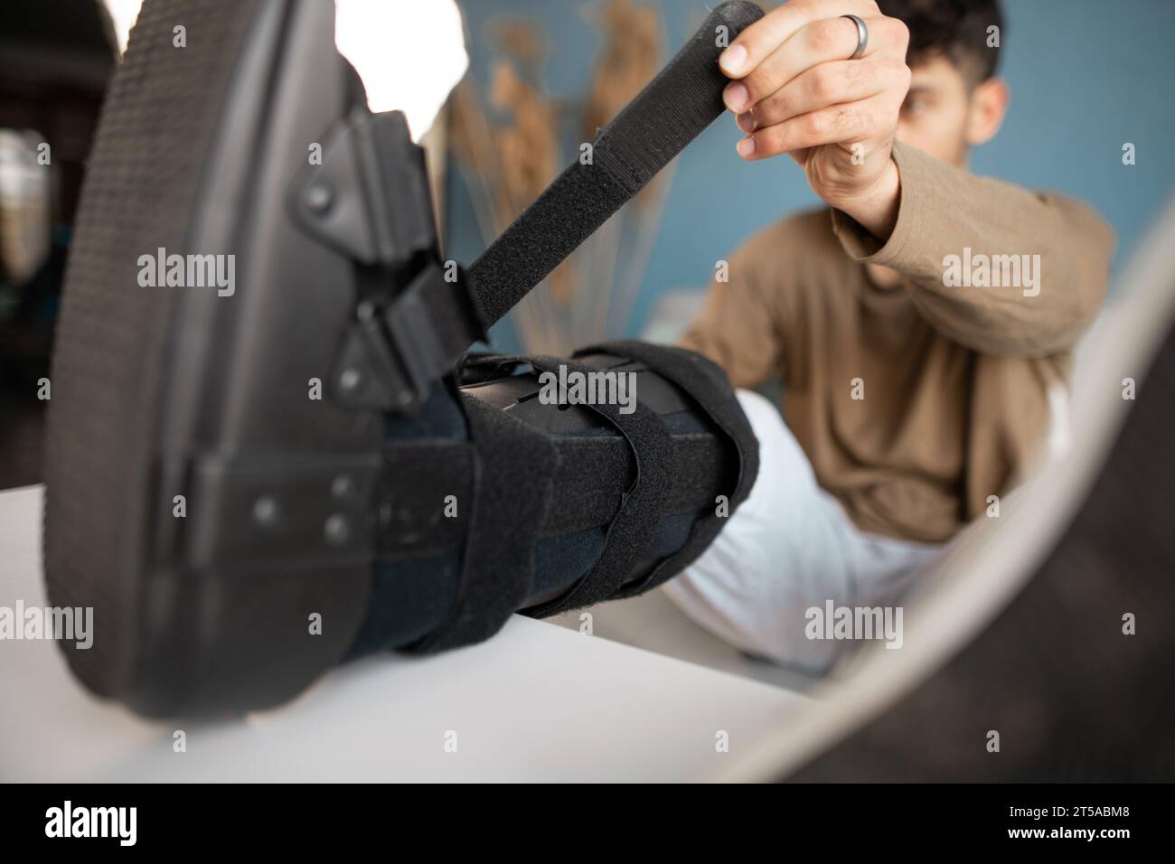 Man putting ankle sprain orthosis, black splint on leg sitting on the ...
