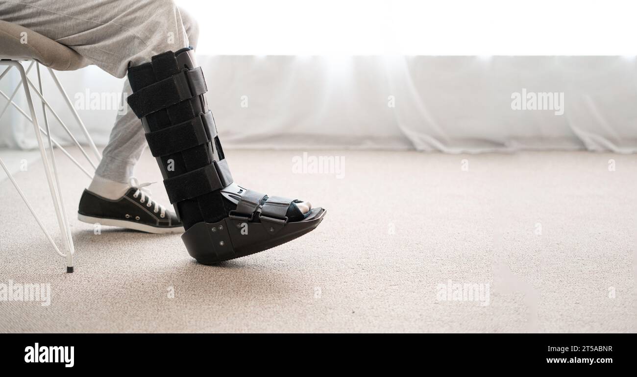 Injury man with black walker splint on leg sitting on the chair. Ankle foot orthosis Stock Photo ...