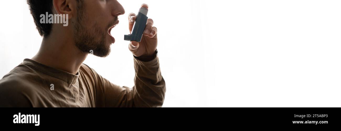 Man uses an inhaler during an asthma attack on white background. Banner ...