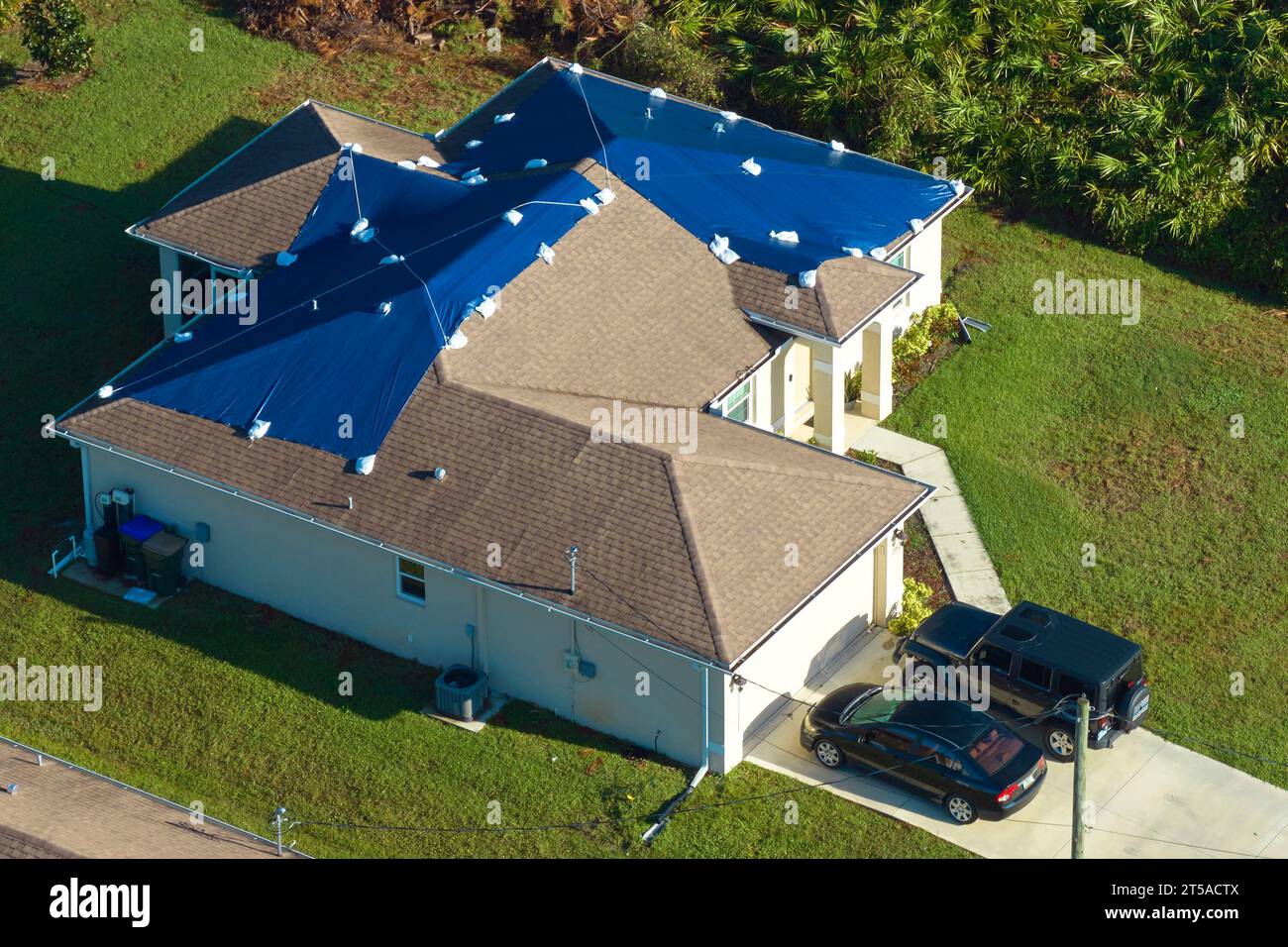 Aerial view of damaged in hurricane Ian house roof covered with blue ...