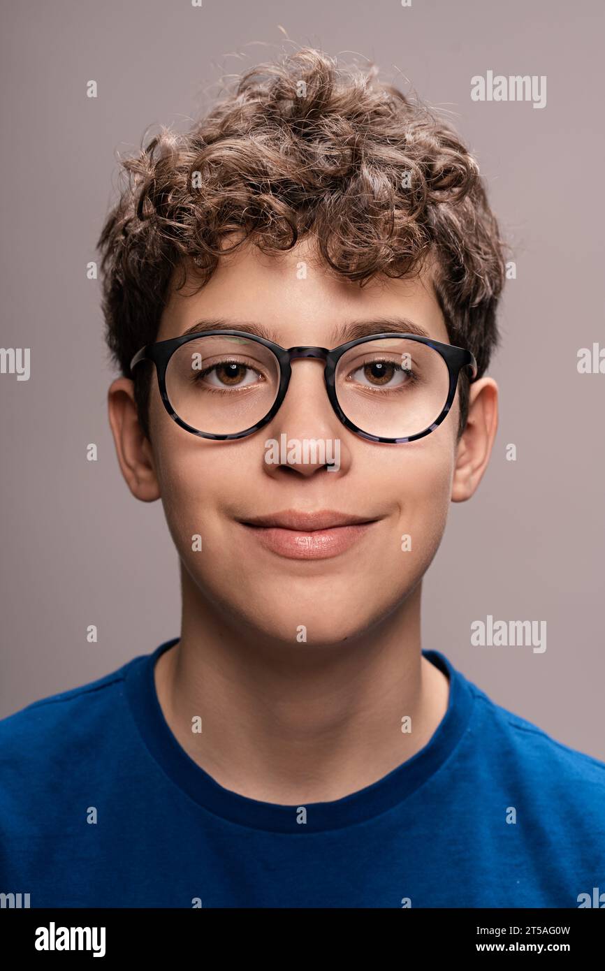 A cheerful teen boy with curly hair and eyeglasses, exuding confidence ...
