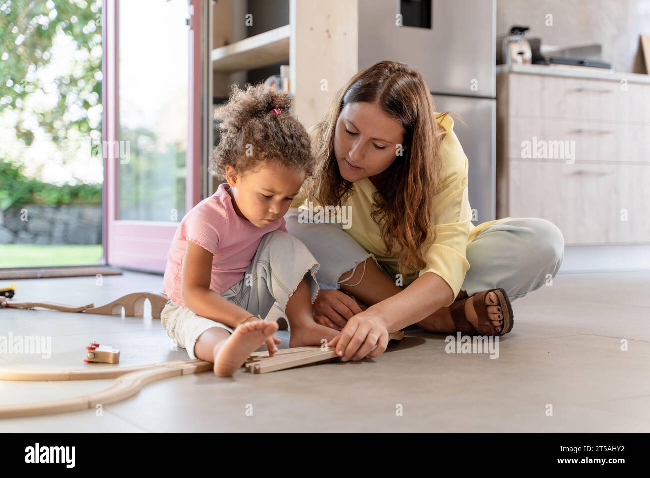 Mother and Child Playing with Toy Train - A mother and her biracial ...