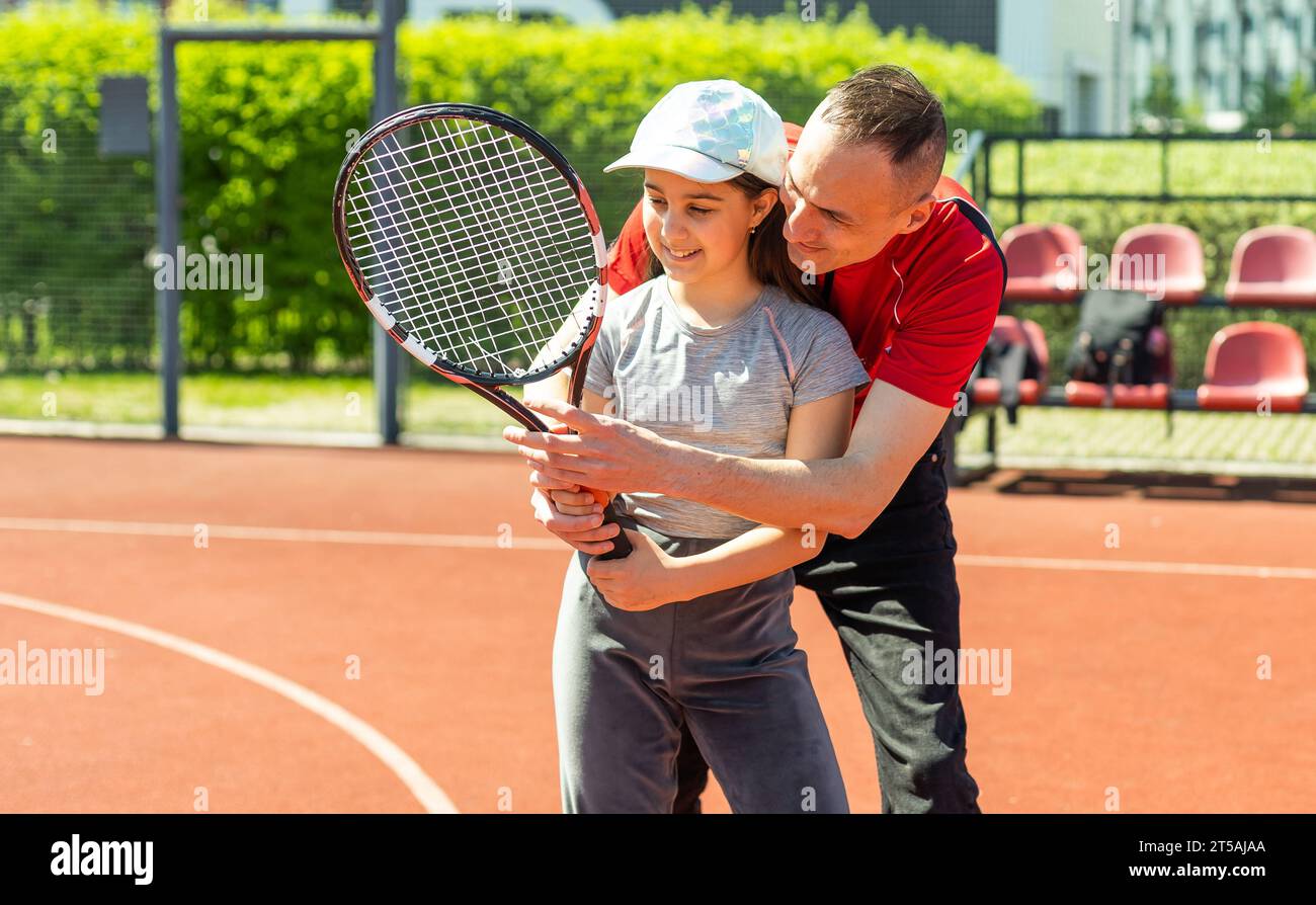 Father is a tennis coach for his daughter. Female child is playing in ...