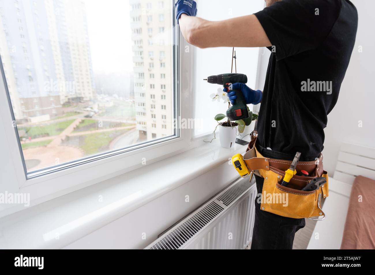 Handsome young man installing bay window in a new house construction ...