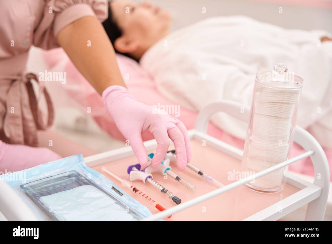 Woman in a pink uniform takes syringe from injection table Stock Photo ...