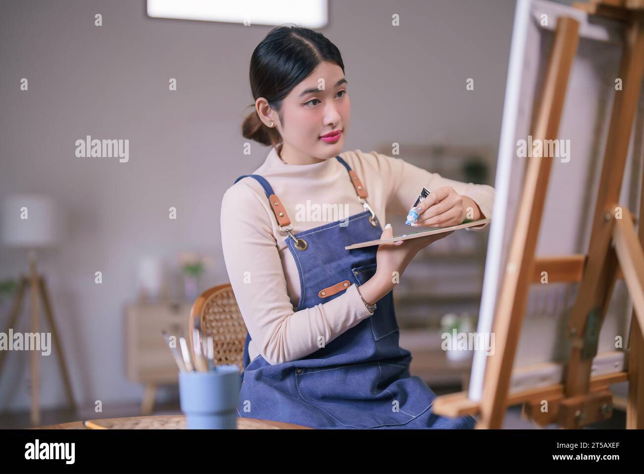 Young asian female artist squeeze color out of tube on color palette ...