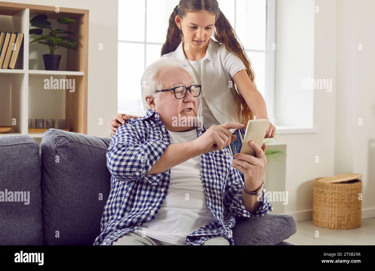 Teenage girl teaching her elderly grandfather to use mobile phone and ...