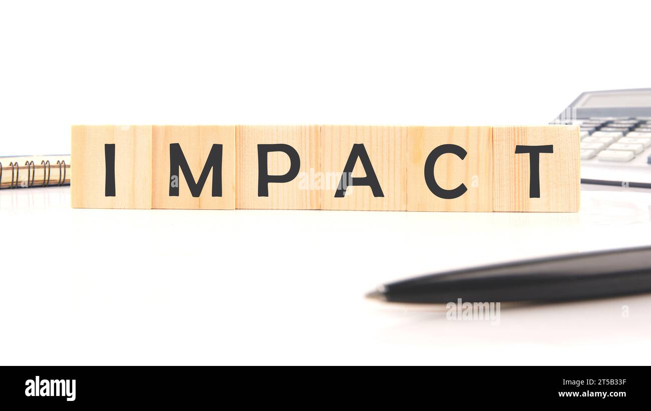 IMPACT word assembled from wooden cubes next to a calculator, pen and ...