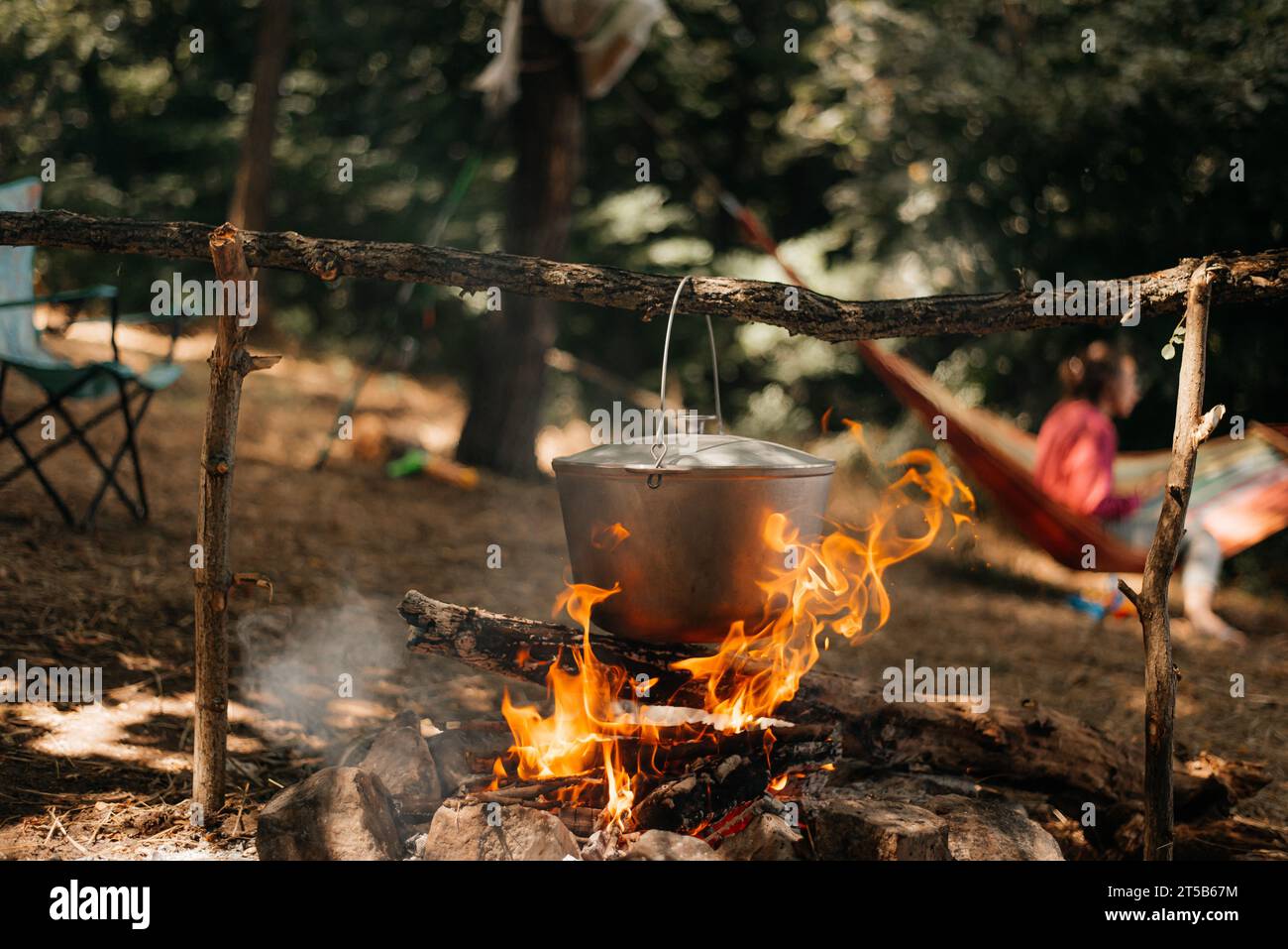 Travel a kettle over a fire burning on the river and sunset backgroun ...