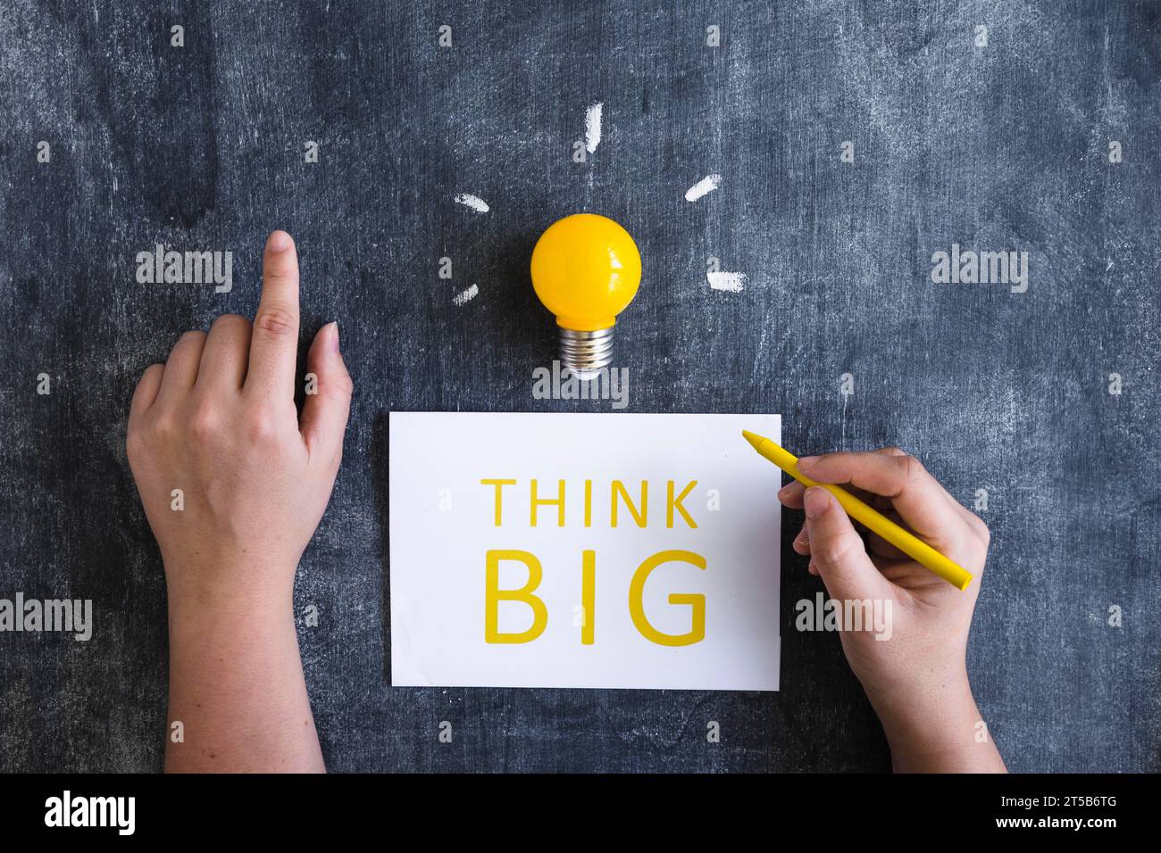 Close up hand writing text think big white paper with yellow light bulb ...
