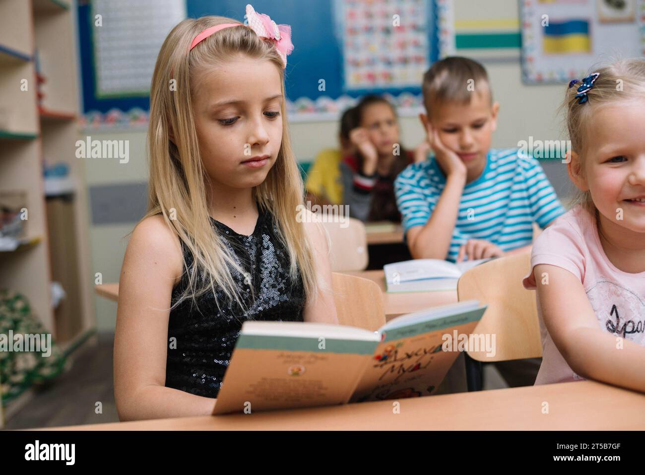 Girl sitting table reading book Stock Photo - Alamy