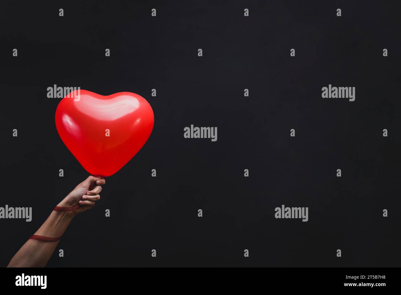 Hand holding heart shaped balloon Stock Photo - Alamy
