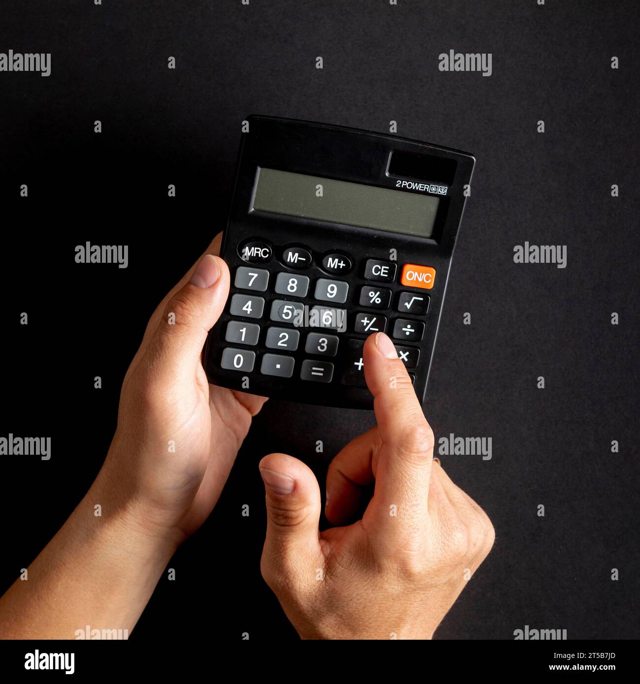 Hands using black mini calculator Stock Photo - Alamy