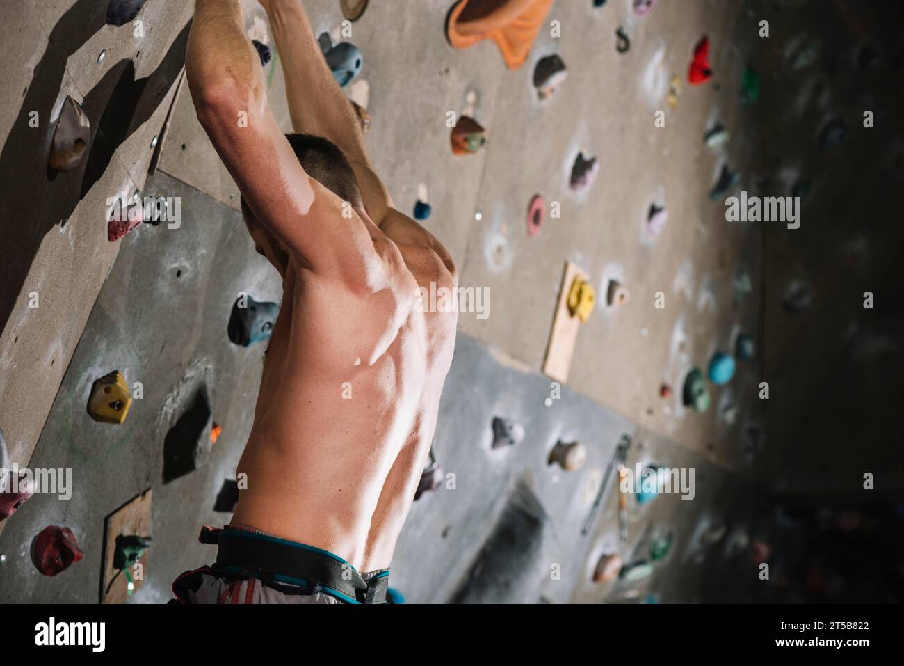 Muscular man hanging climbing wall Stock Photo - Alamy