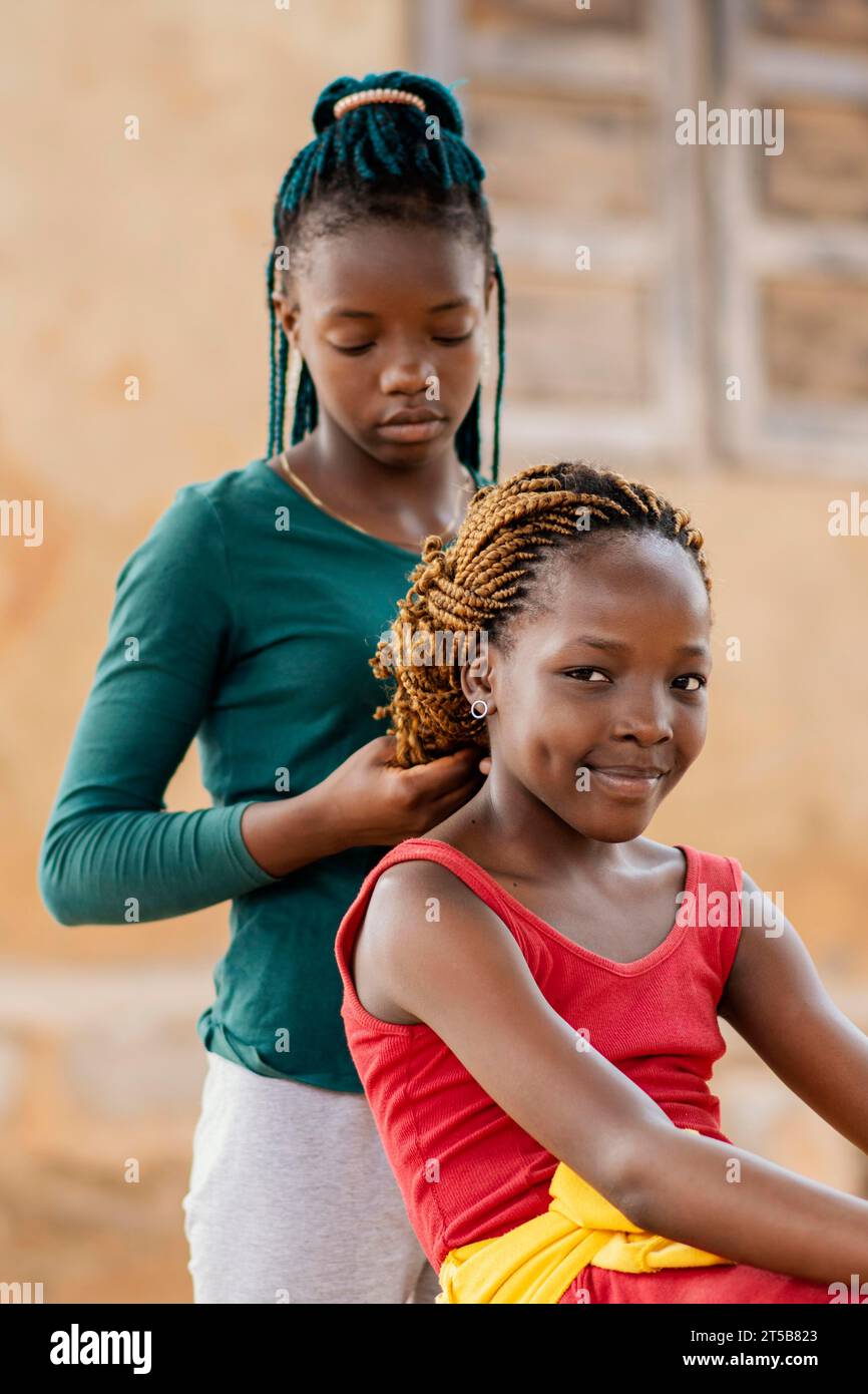 Medium shot girl braiding friend s hair Stock Photo - Alamy
