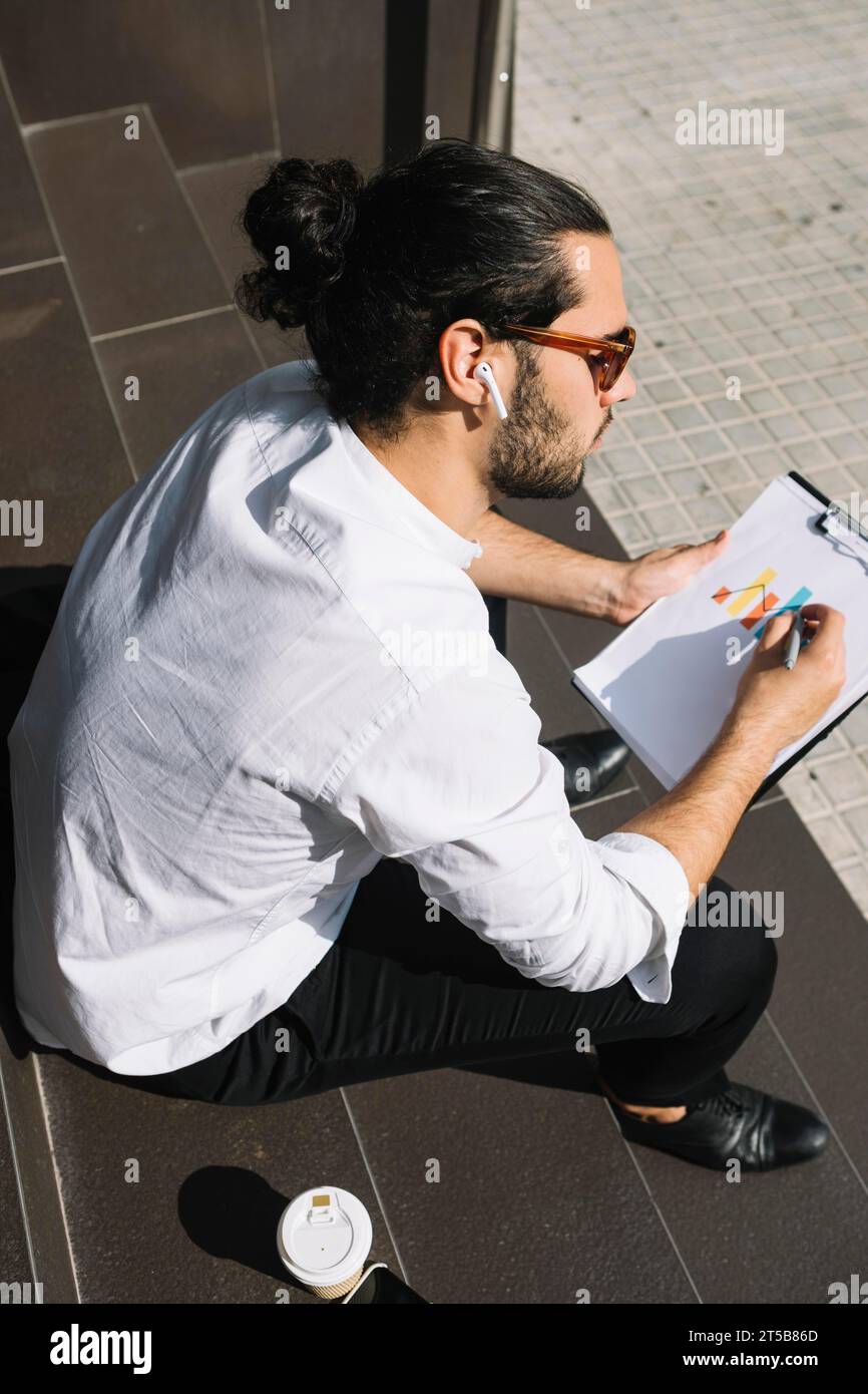Overhead view businessman sitting staircase drawing graph clipboard ...