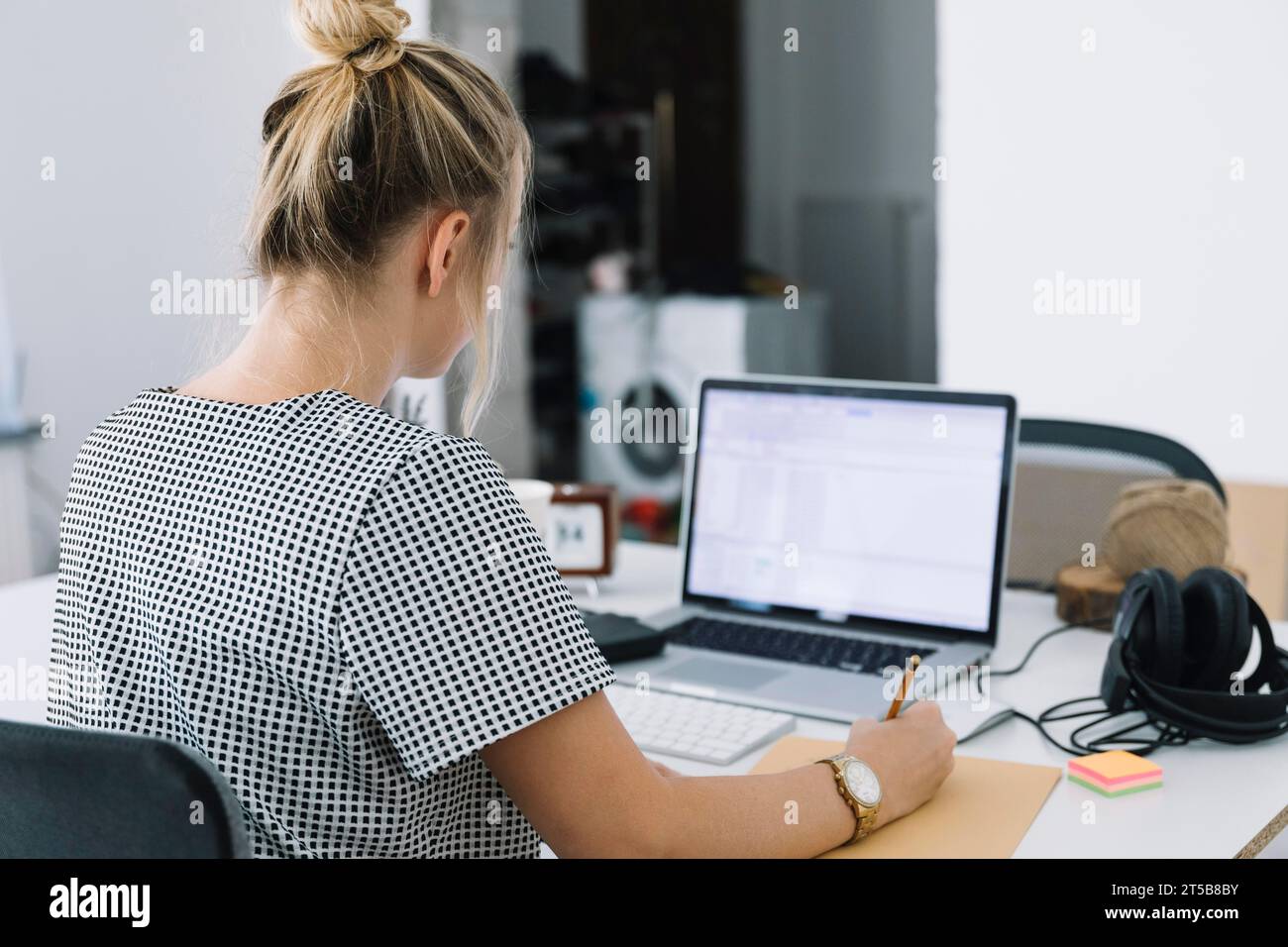 Rear view businesswoman writing notes brown paper with laptop desk ...