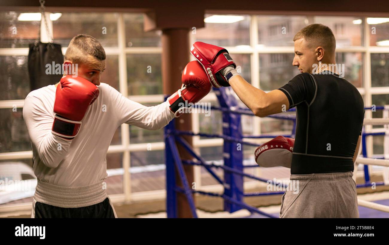 Side view male boxer practicing with trainer ring Stock Photo - Alamy