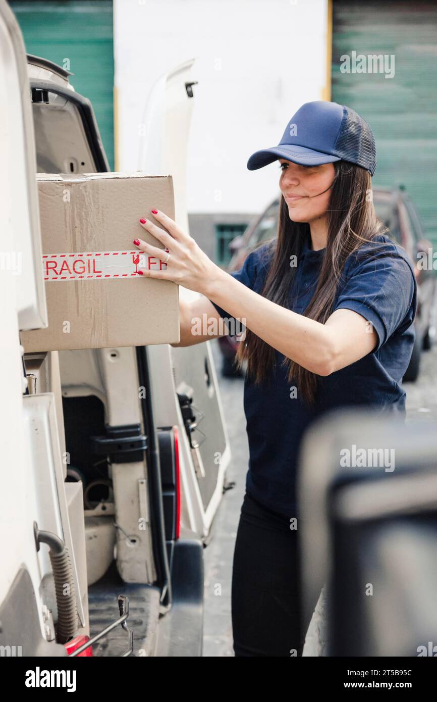 Young female courier unloaded cardboard box from vehicle Stock Photo ...