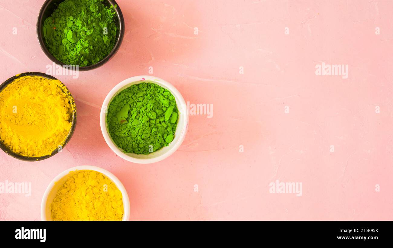 Yellow green holi color powder pink background Stock Photo - Alamy