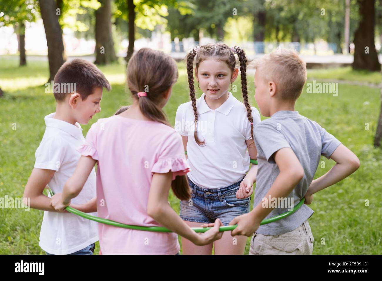 Boys girls playing with hula hoop Stock Photo - Alamy