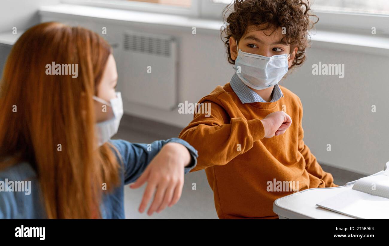 Children with medical masks doing elbow salute class Stock Photo - Alamy