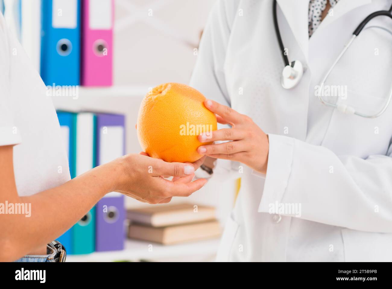 Close up doctor patient holding orange Stock Photo - Alamy