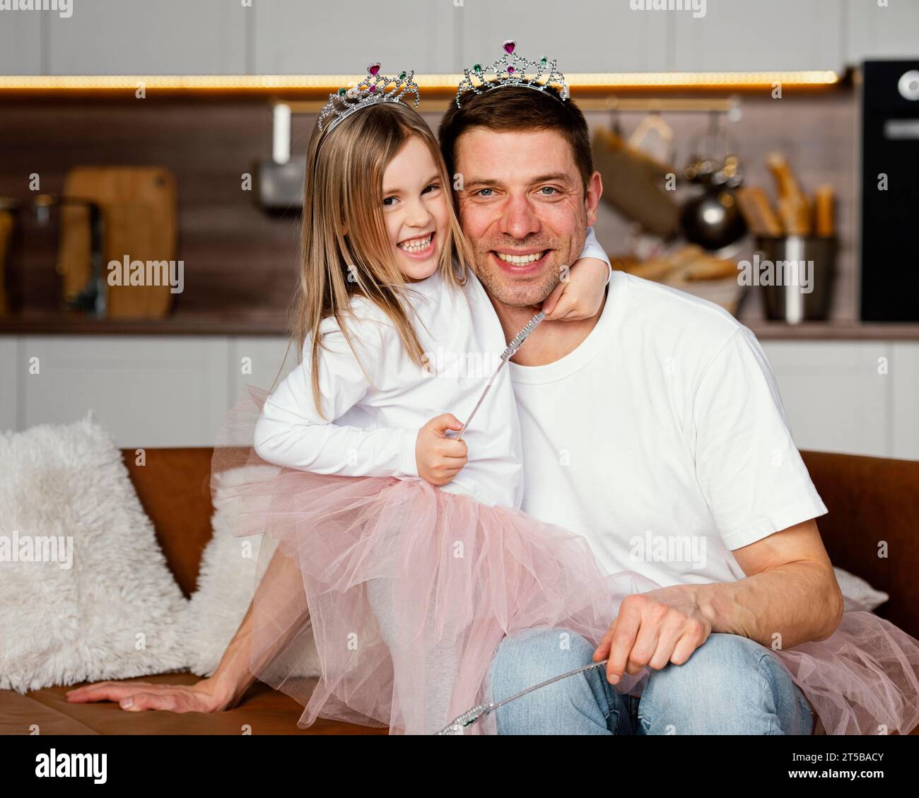 Front view smiley father daughter playing with tiara wand together ...