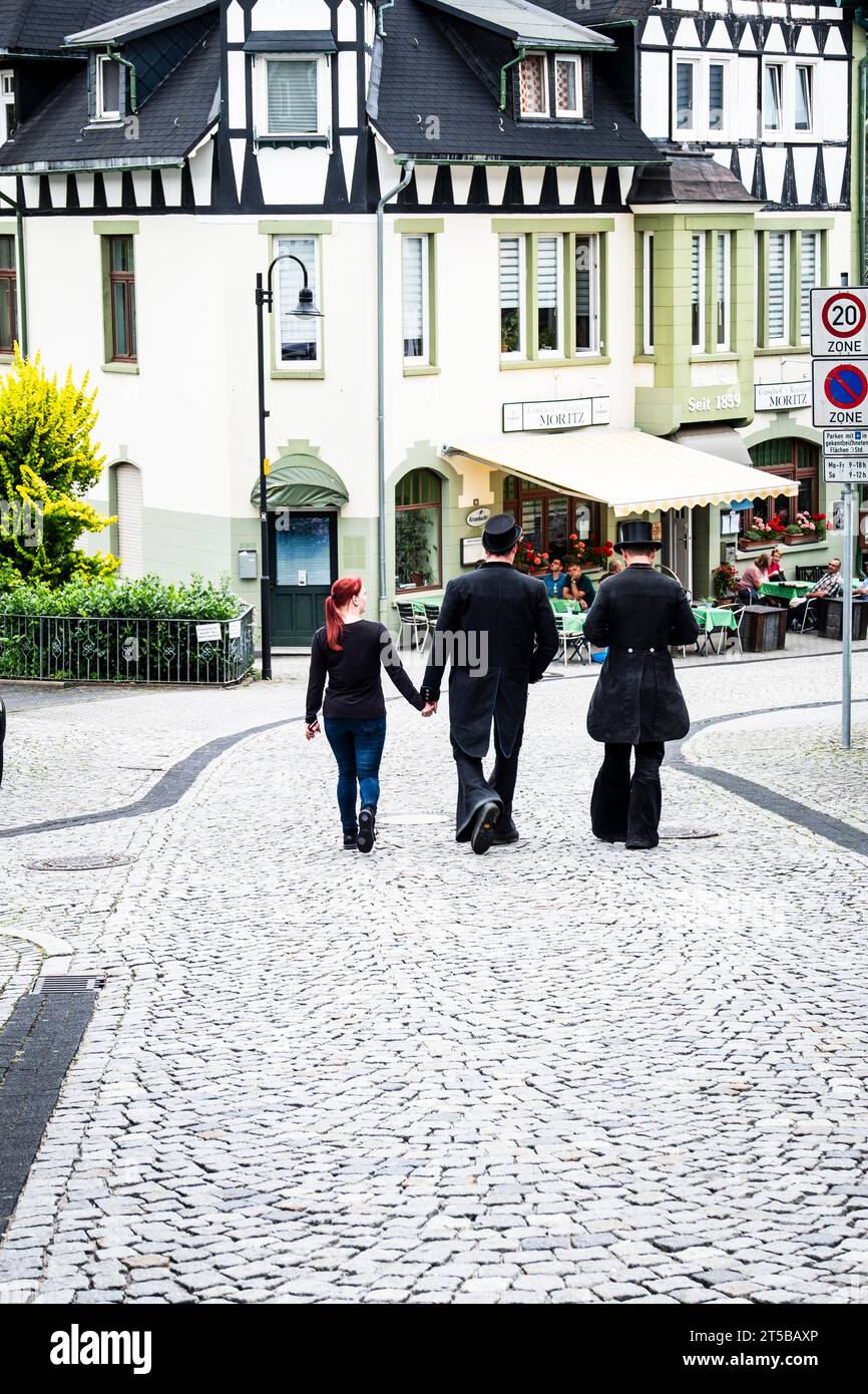 Three people, two in traditional traditional costume, walking through ...