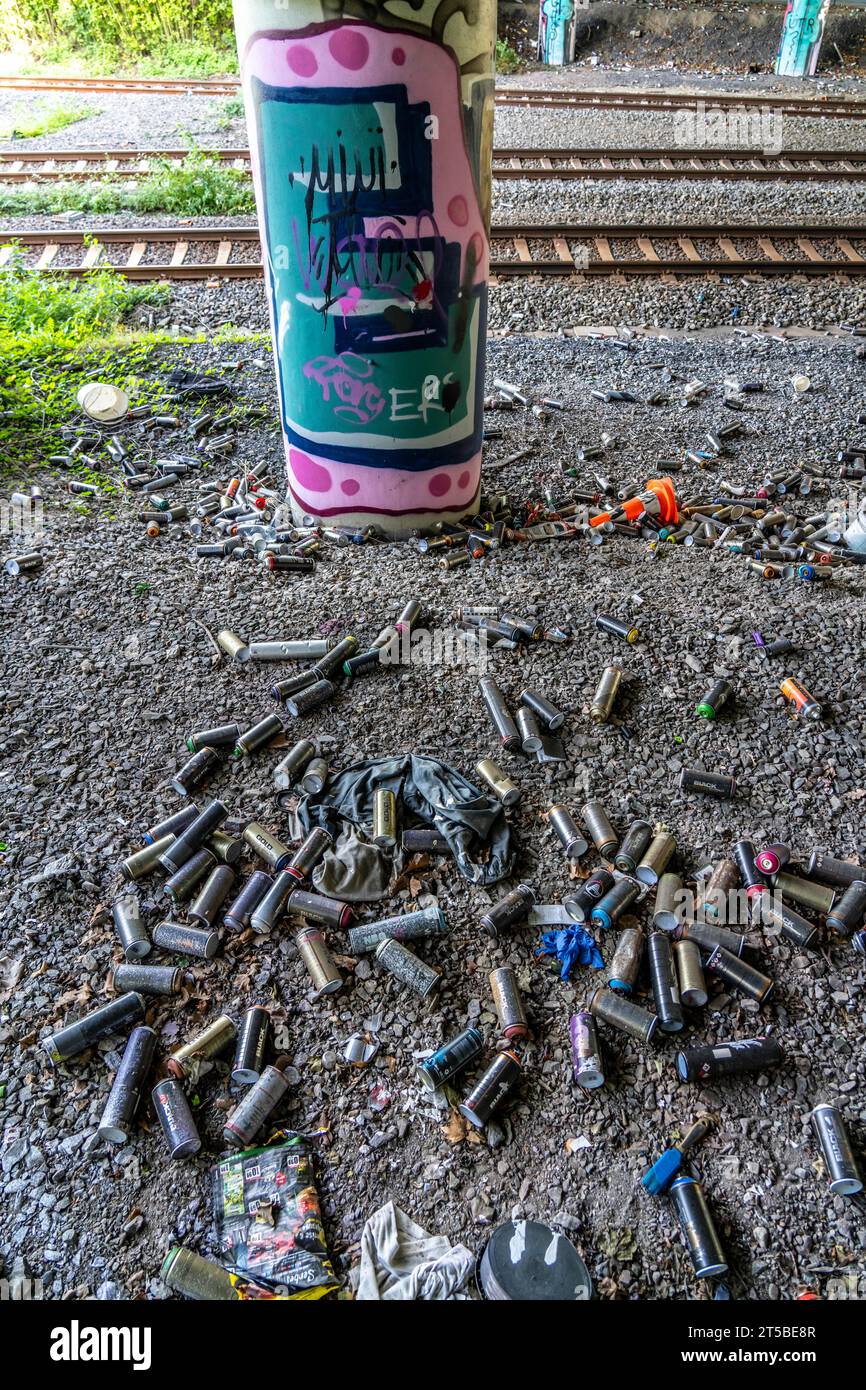 Empty spray paint cans, on a railway track below a road bridge, thrown ...