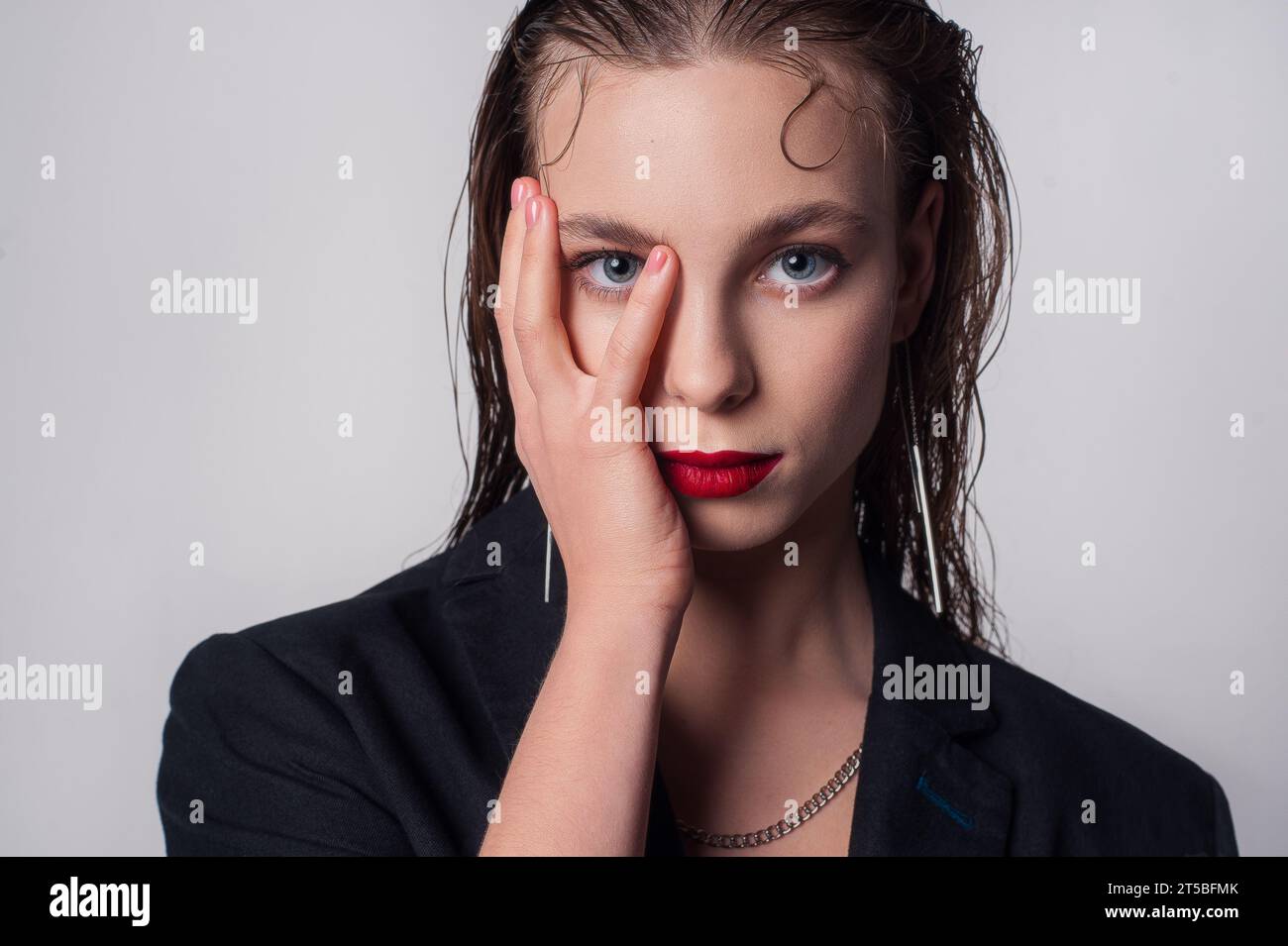 girl covers her face with her hand on a white background with wet ...