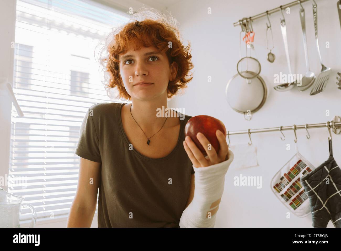teenage girl with broken arm in cast in kitchen sitting on countertop ...