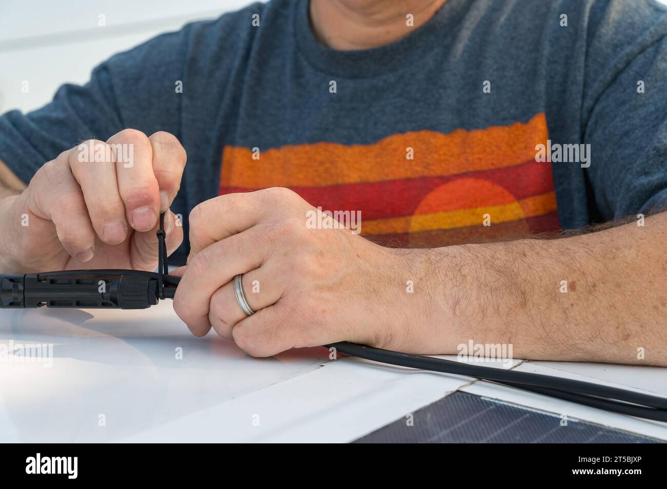 Man pulling a zip tie tight to secure a solar panel connection Stock ...