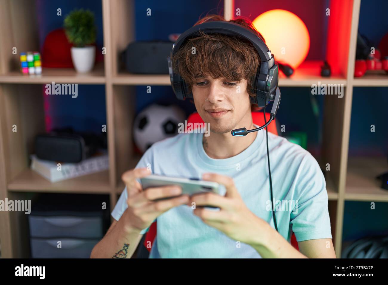 Young blond man streamer playing video game using smartphone at gaming ...
