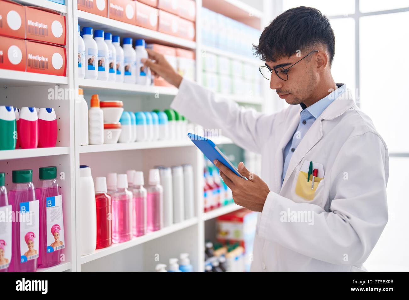 Young hispanic man pharmacist using touchpad working at pharmacy Stock ...