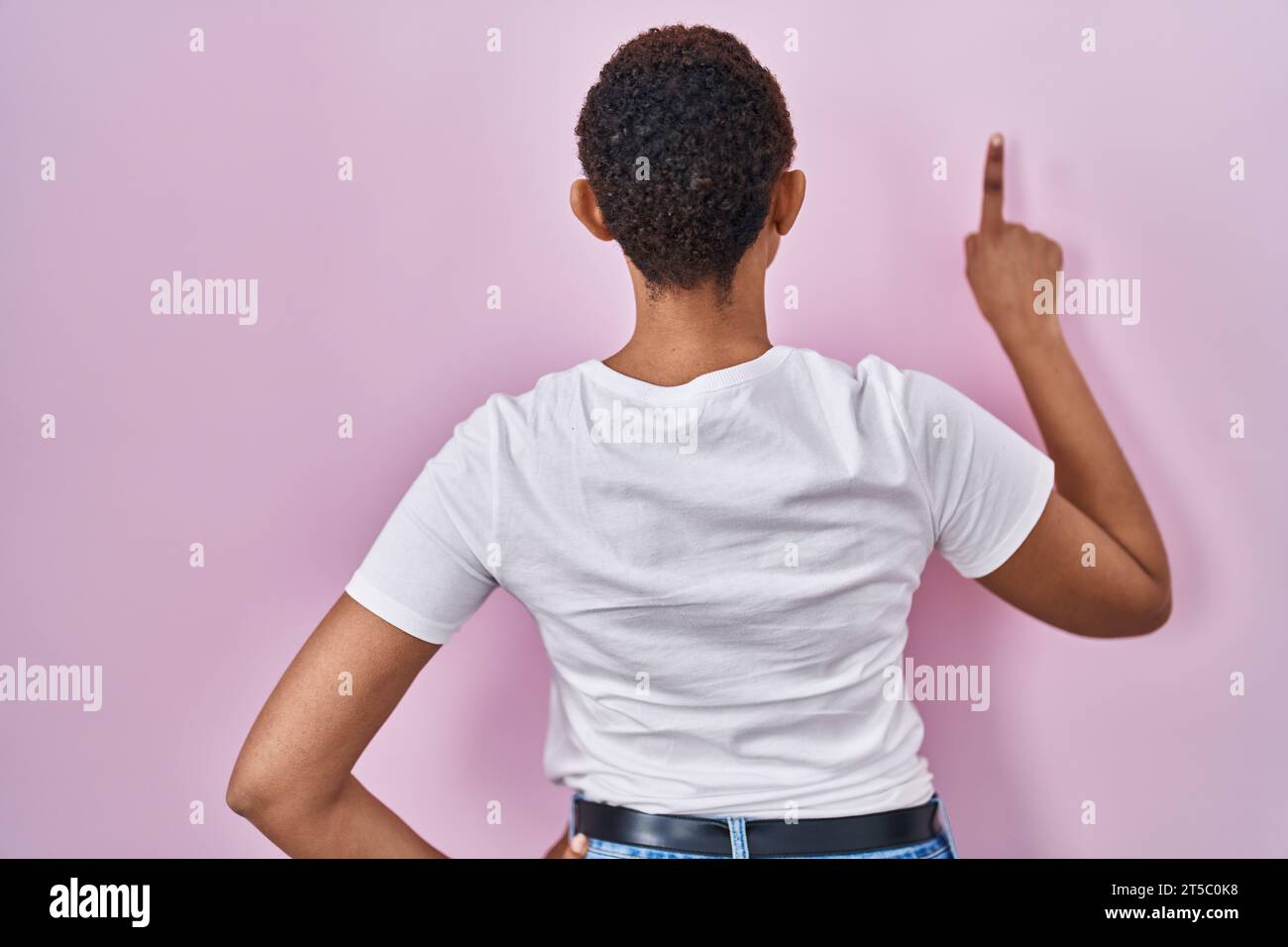 Beautiful african american woman standing over pink background posing ...