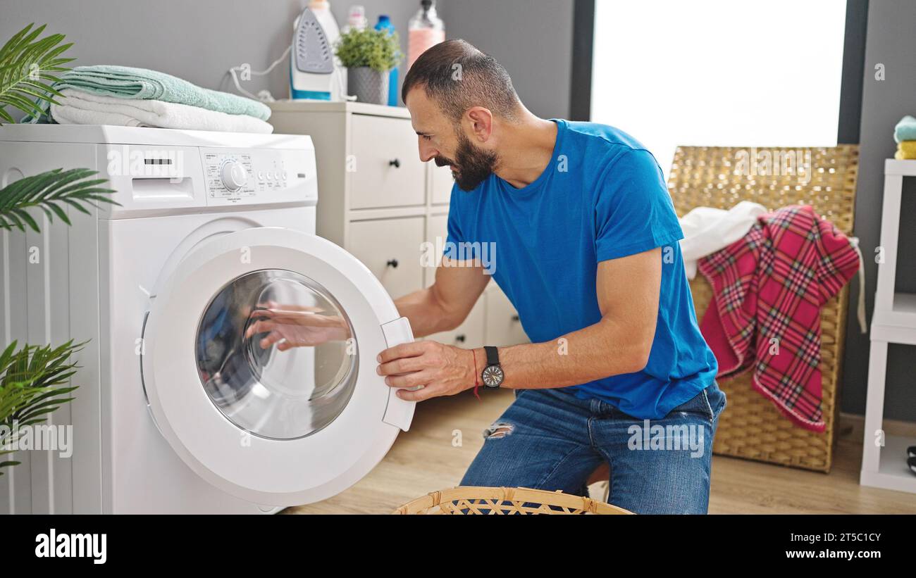 Young hispanic man washing clothes at laundry room Stock Photo - Alamy