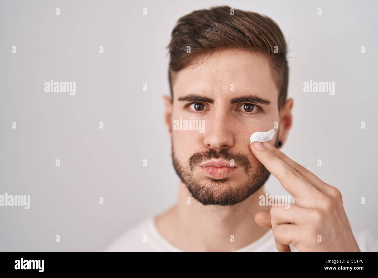 Hispanic man with beard using moisturizer facial cream puffing cheeks ...