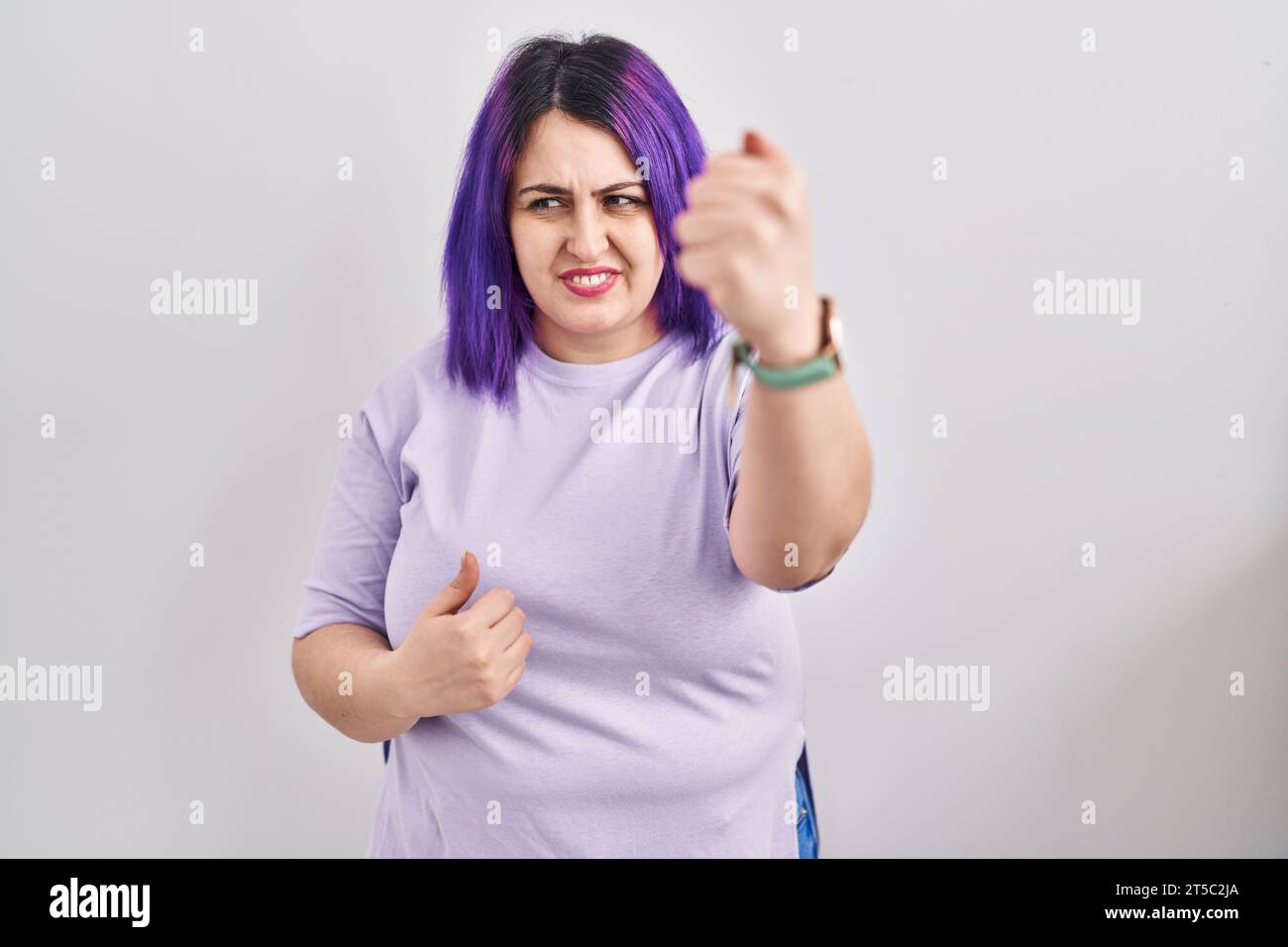 Plus size woman wit purple hair standing over isolated background angry ...