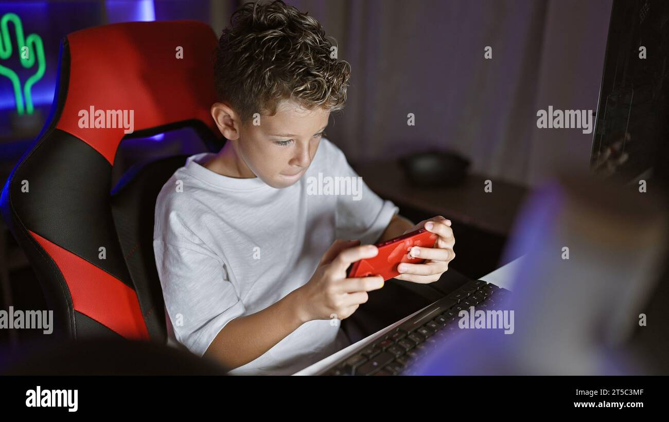 Adorable blond boy streamer, engrossed in serious game playing, live ...
