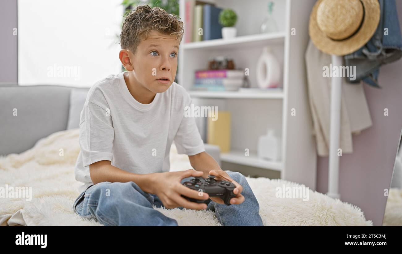 Adorable blond boy comfortably sitting on sofa at home, intensely ...