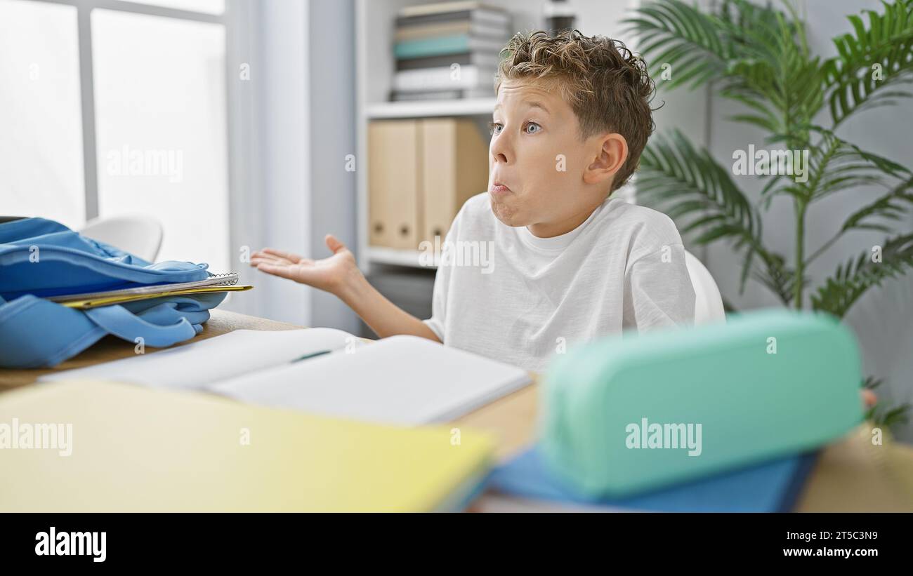 Adorable blond boy, an uncertain student, in a classroom setting ...