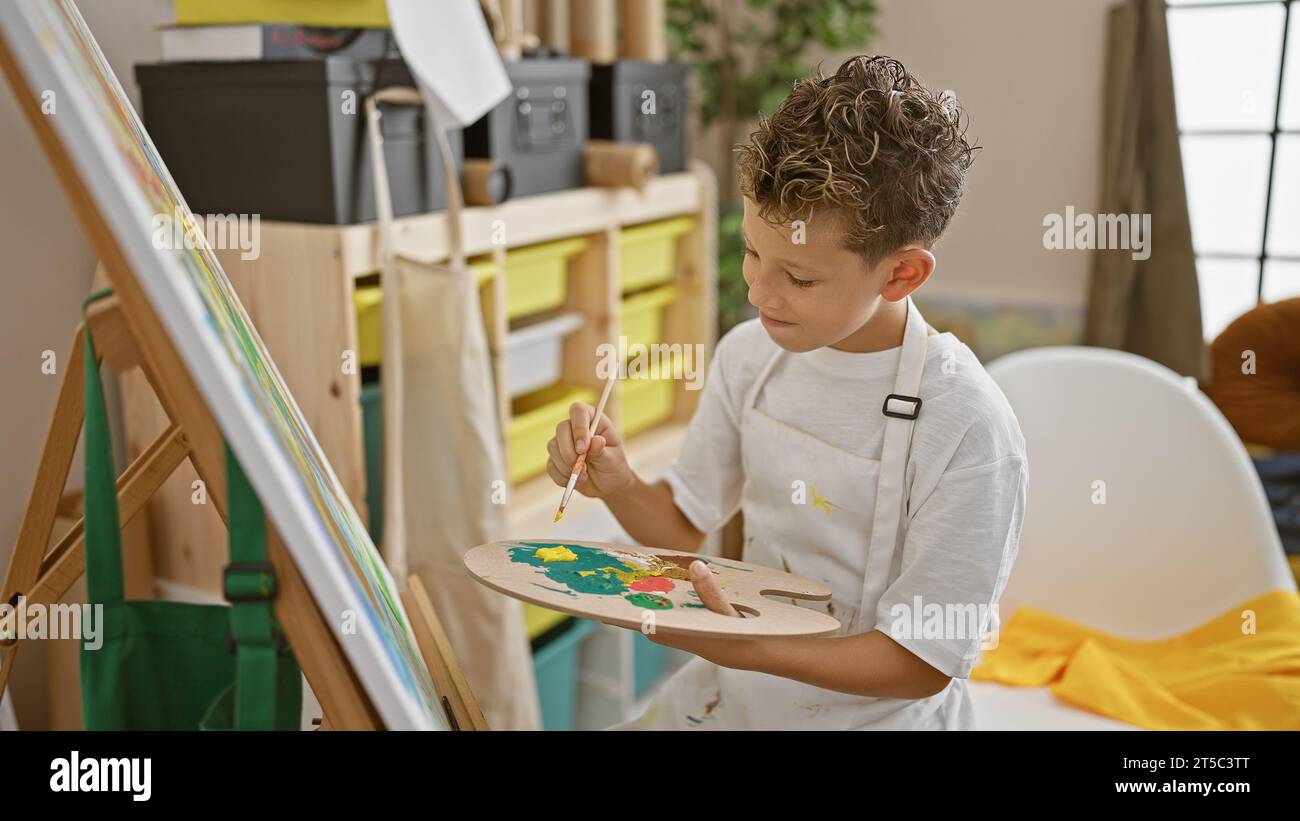 Adorable blond boy artist confidently sitting on chair, drawing at ...