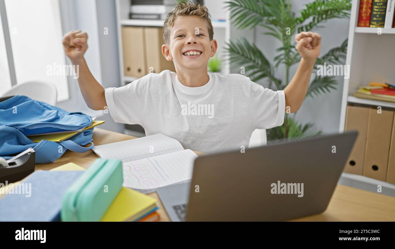 Adorable blond boy student celebrating academic win, studying with ...