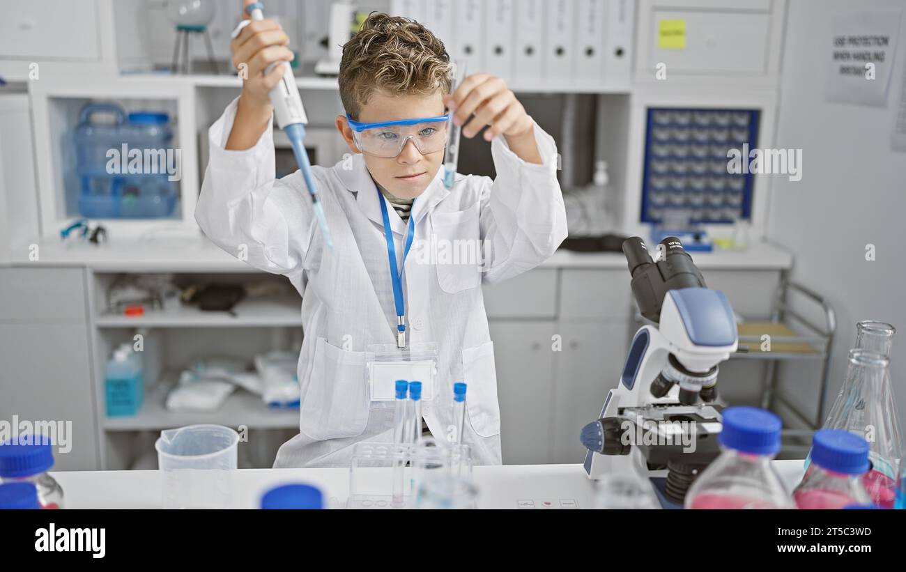 Adorable blond boy scientist working at laboratory, measuring liquid in ...